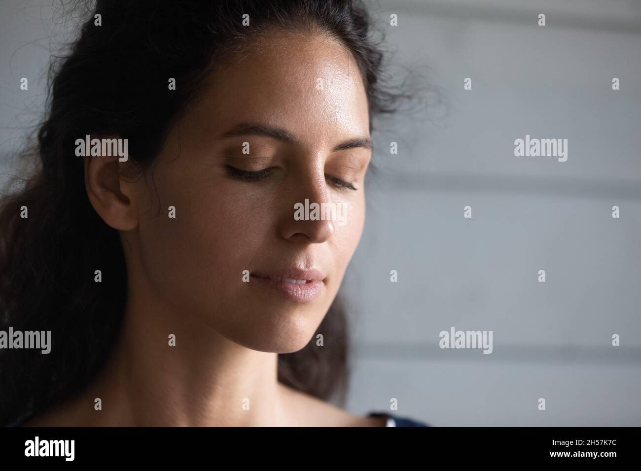 Calm millennial hispanic female looking down with closed eyes Stock ...