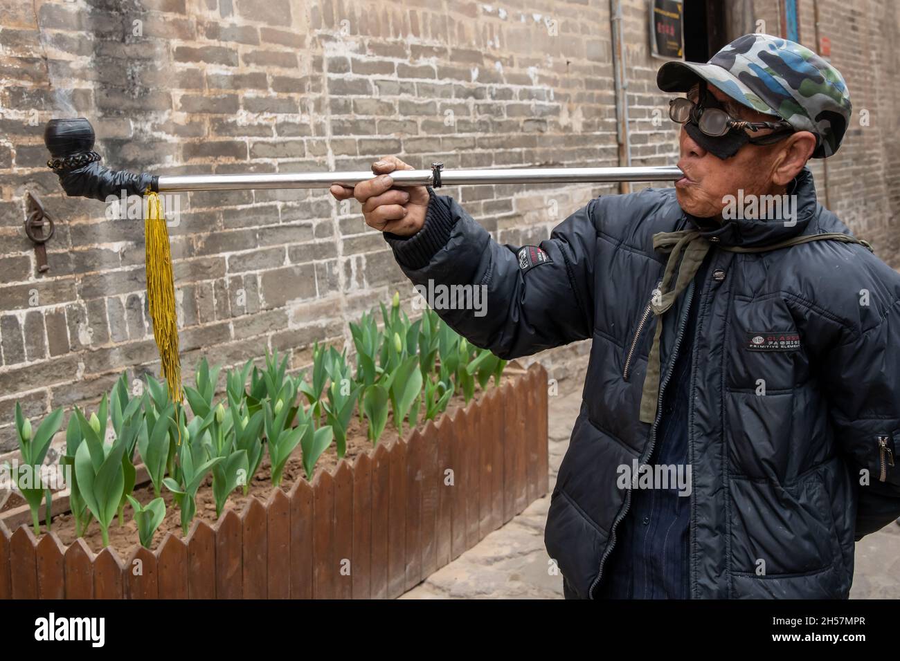 Old Chinese Man smoking a long pipe in the 14th century Dangjia Village ...