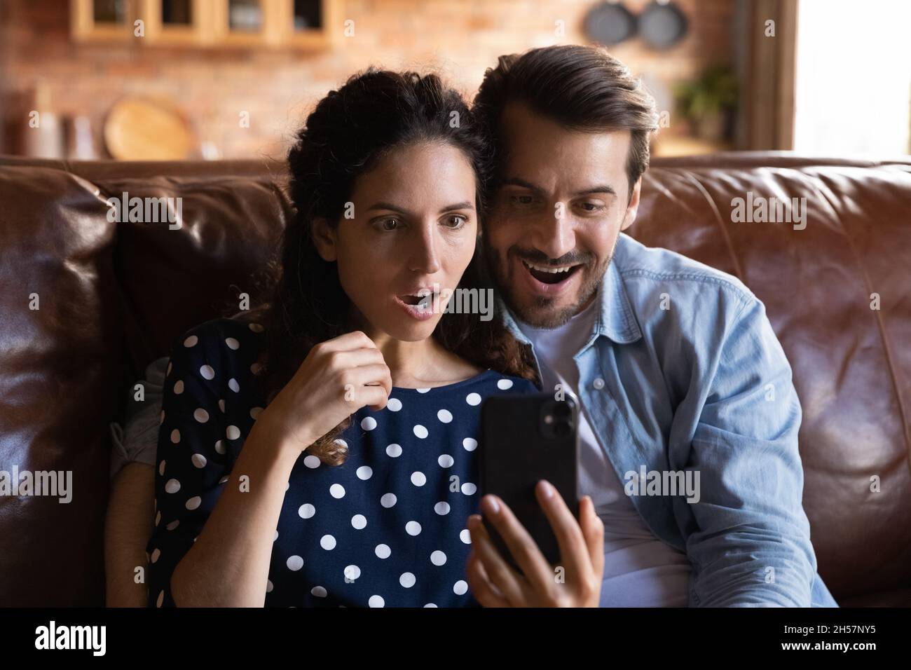 Shocked family couple sit on couch look on smartphone screen Stock ...