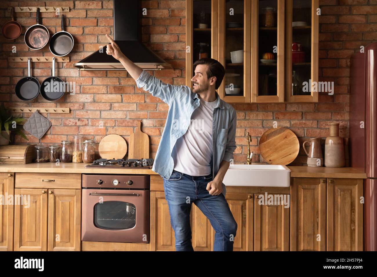 Funny millennial man enjoy cooking dance at modern wooden kitchen Stock ...