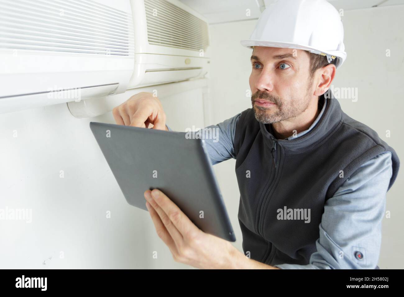man carefully checking a new installed ac Stock Photo - Alamy
