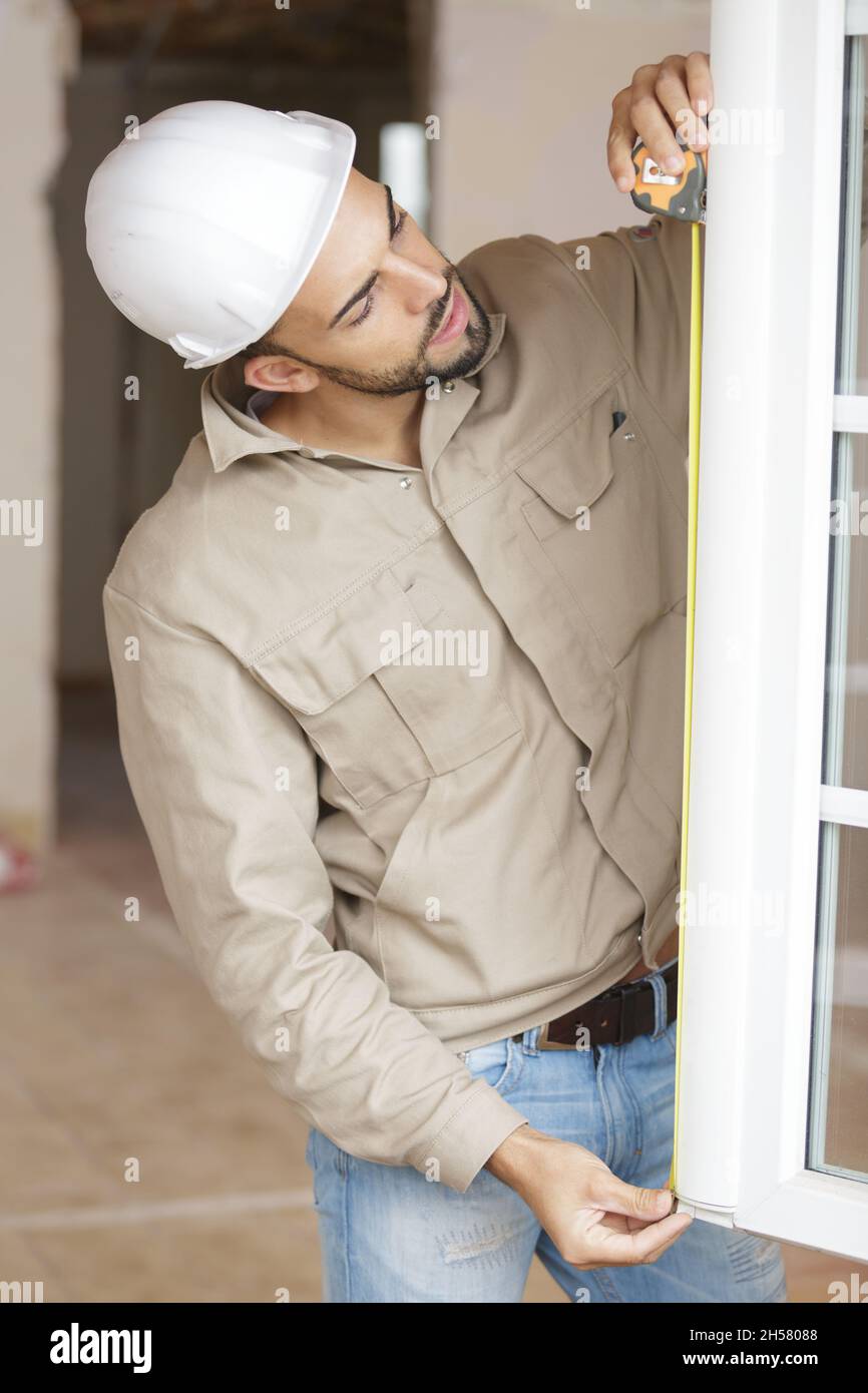 a male builder is measuring a window Stock Photo - Alamy