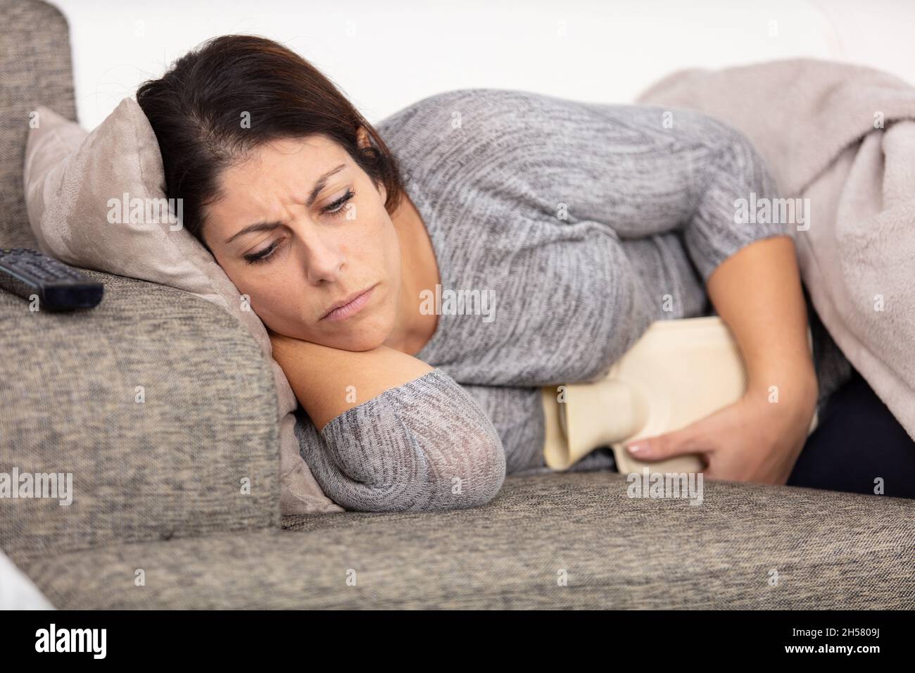 brunette sick woman laying on the couch Stock Photo - Alamy