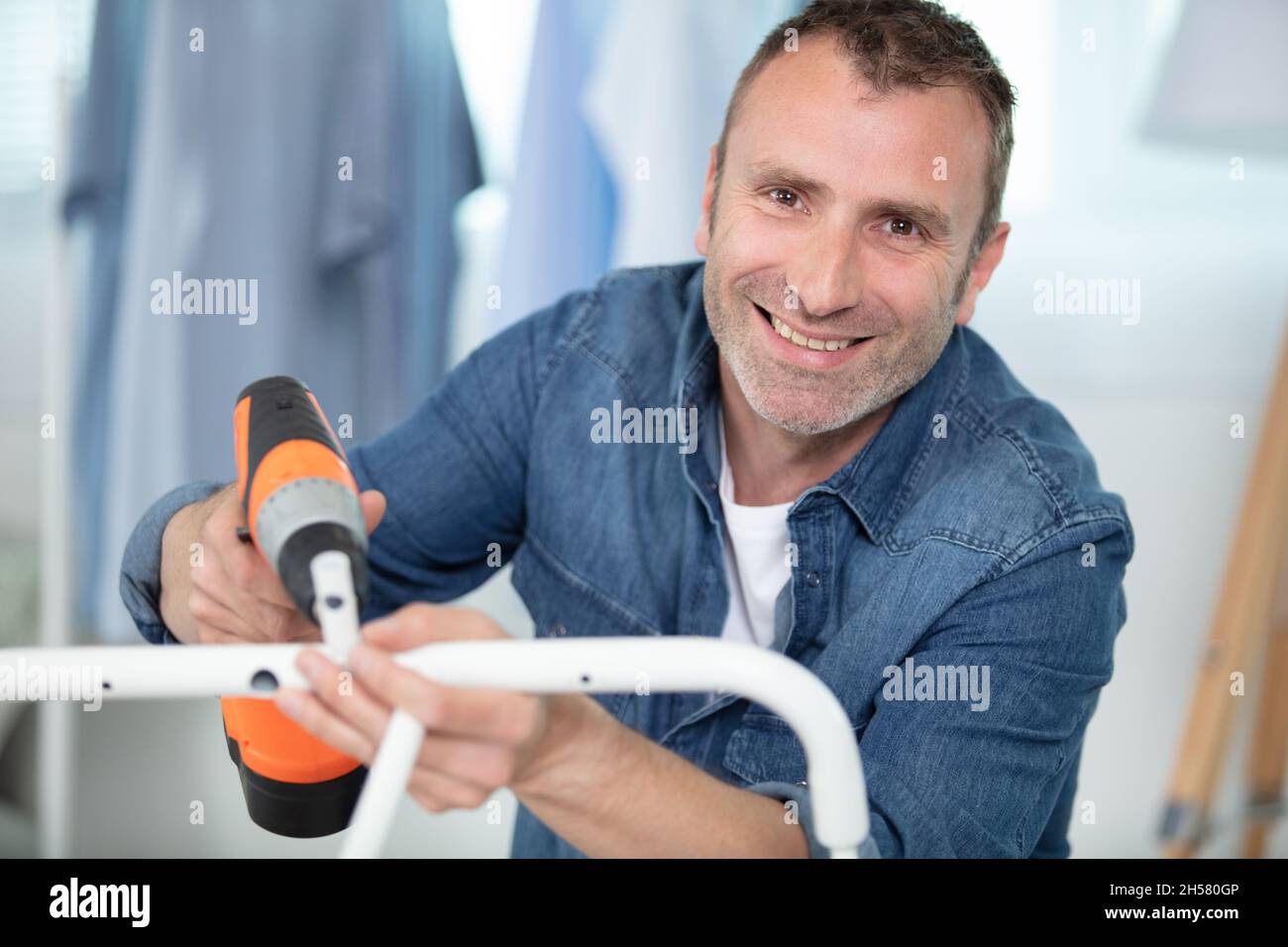 man assembles metal rail with a cordless screwdriver Stock Photo - Alamy