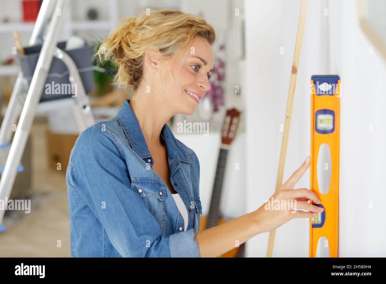 woman leaning a spirit level on the wall Stock Photo - Alamy