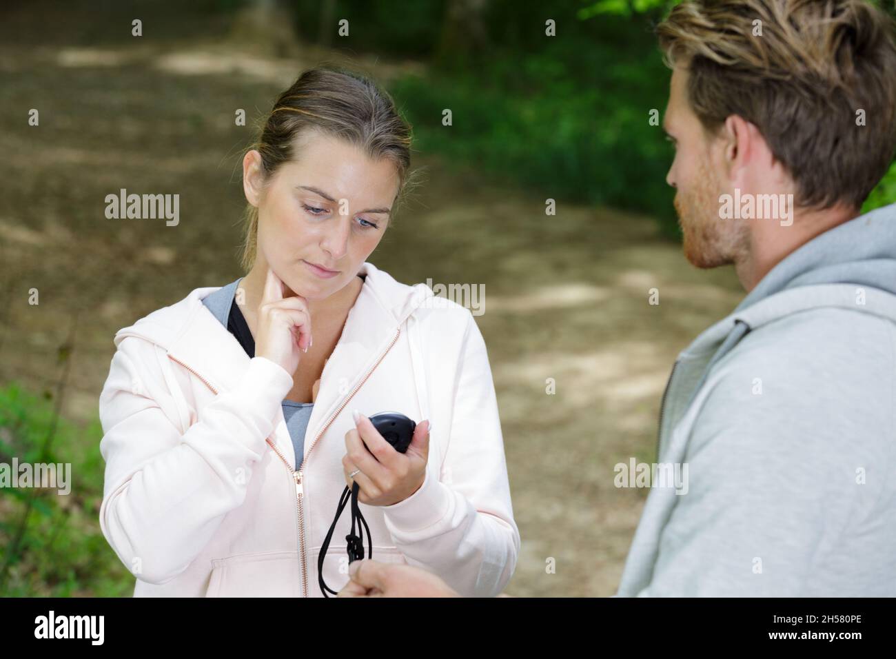 female coach timing runner in a park Stock Photo - Alamy