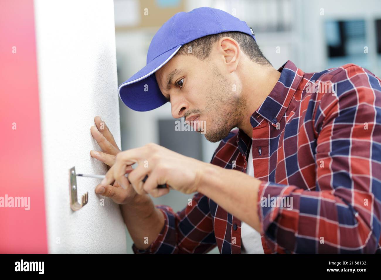 young working man fixing clothes hook on wall Stock Photo - Alamy