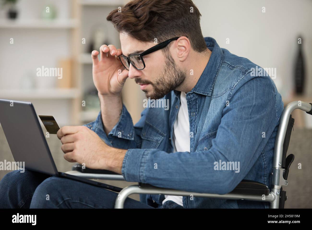 disabled person holds credit card and uses a pc Stock Photo - Alamy
