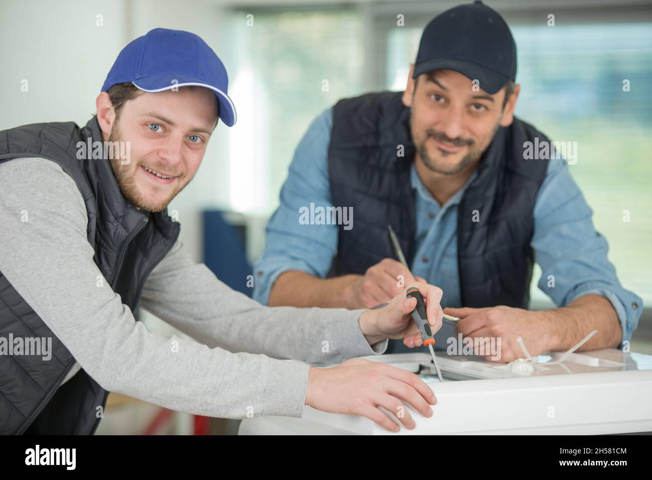 two men at work using a screwdriver Stock Photo - Alamy