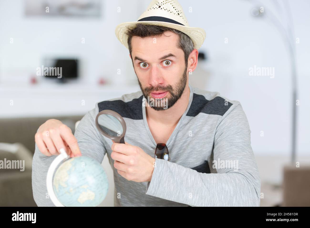man looking at globe through magnifying glass Stock Photo - Alamy
