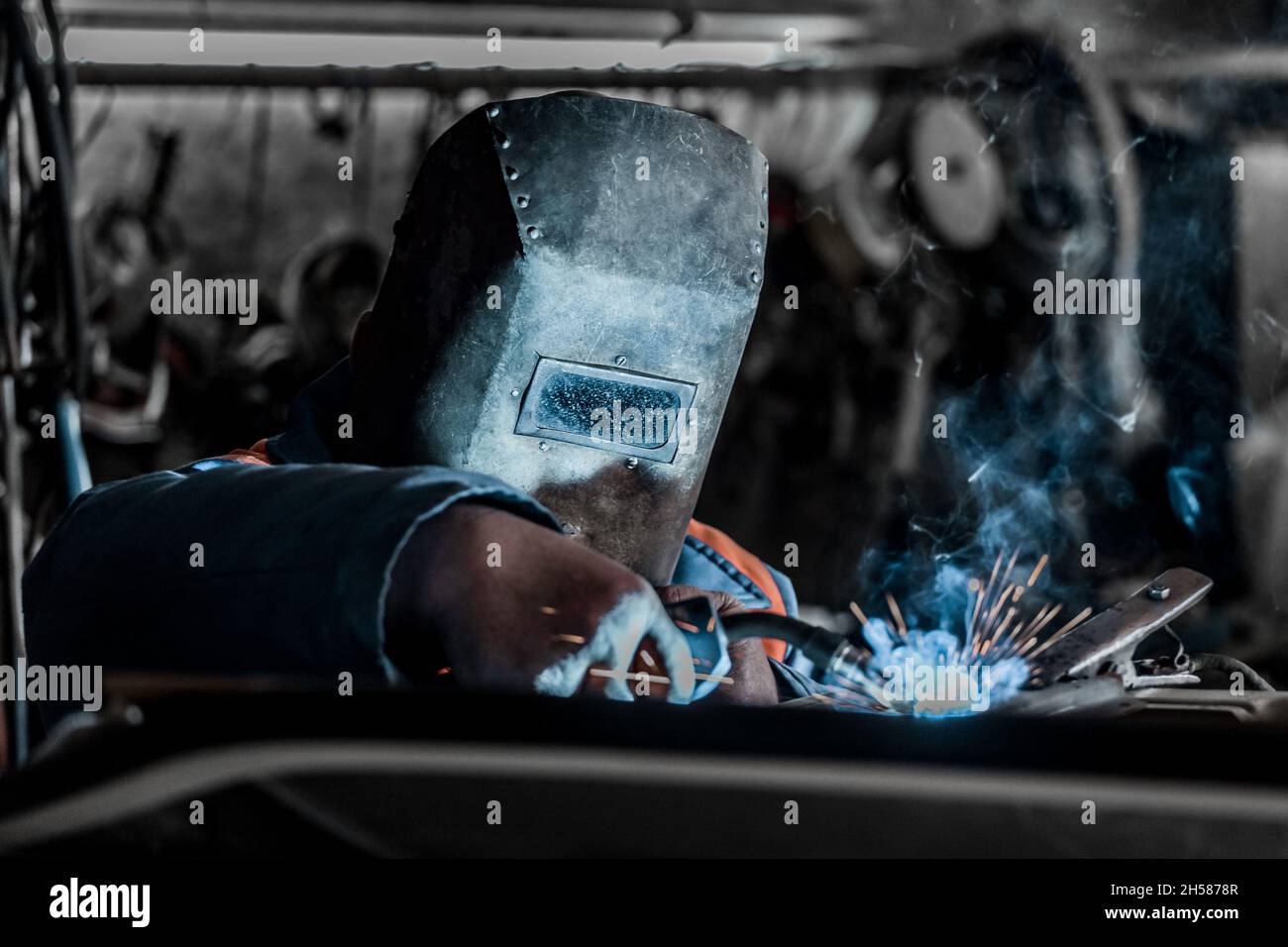 Welder industrial worker in the protective shield is engaged in welding ...