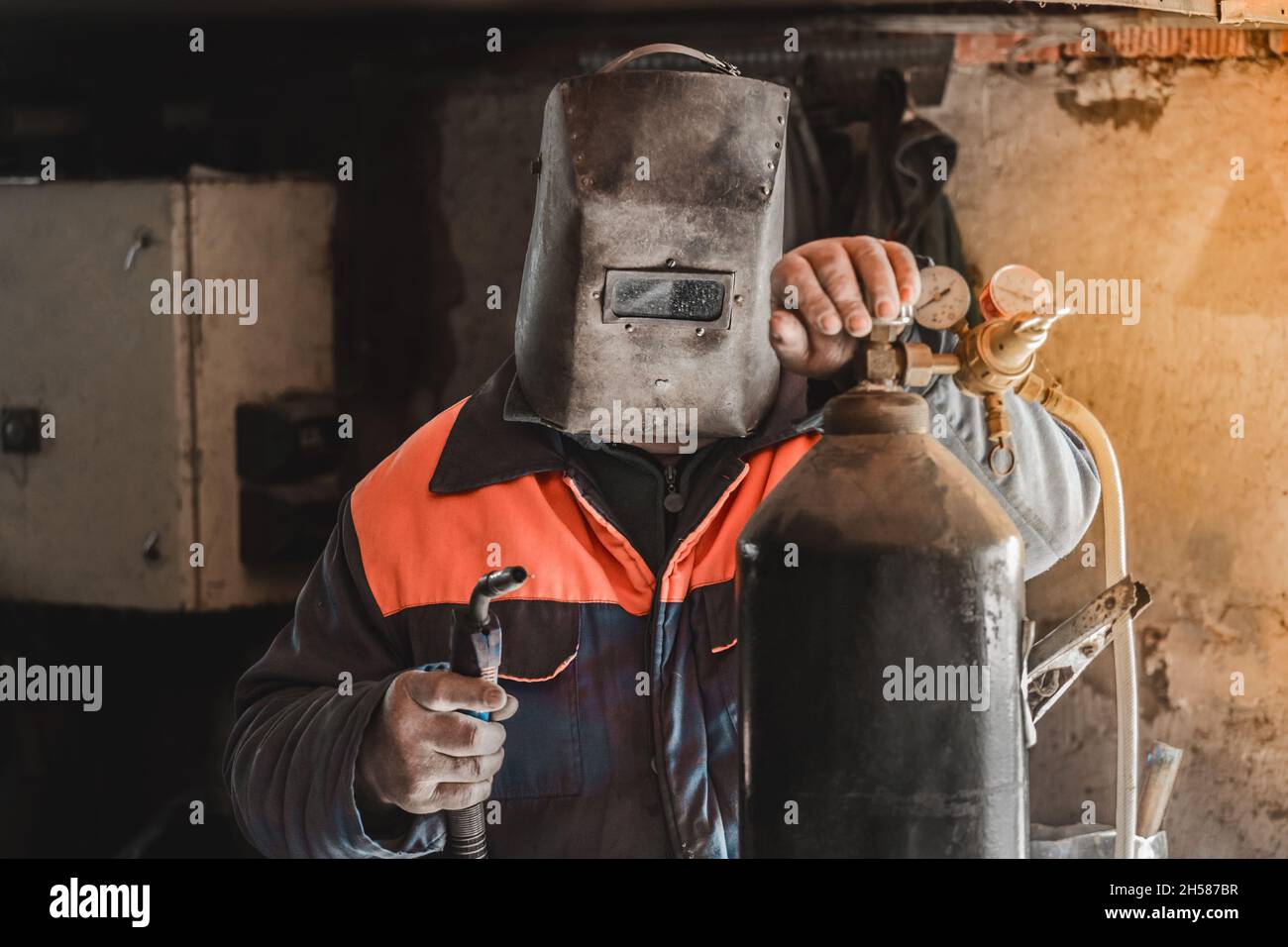 A man welder worker stands in front of a welding machine and a carbon ...