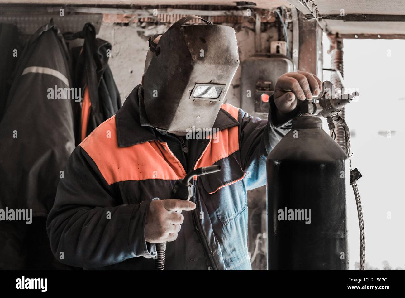 A man welder worker stands in front of a welding machine and a carbon ...