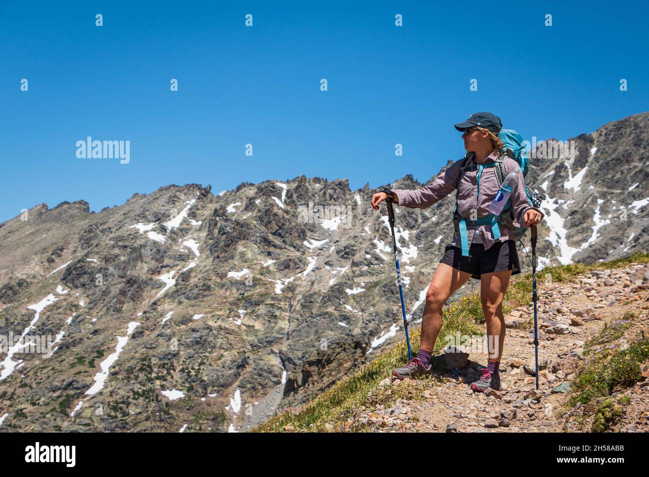 Woman hiker with hiking poles on a sunny day on a steep trail in rugged ...