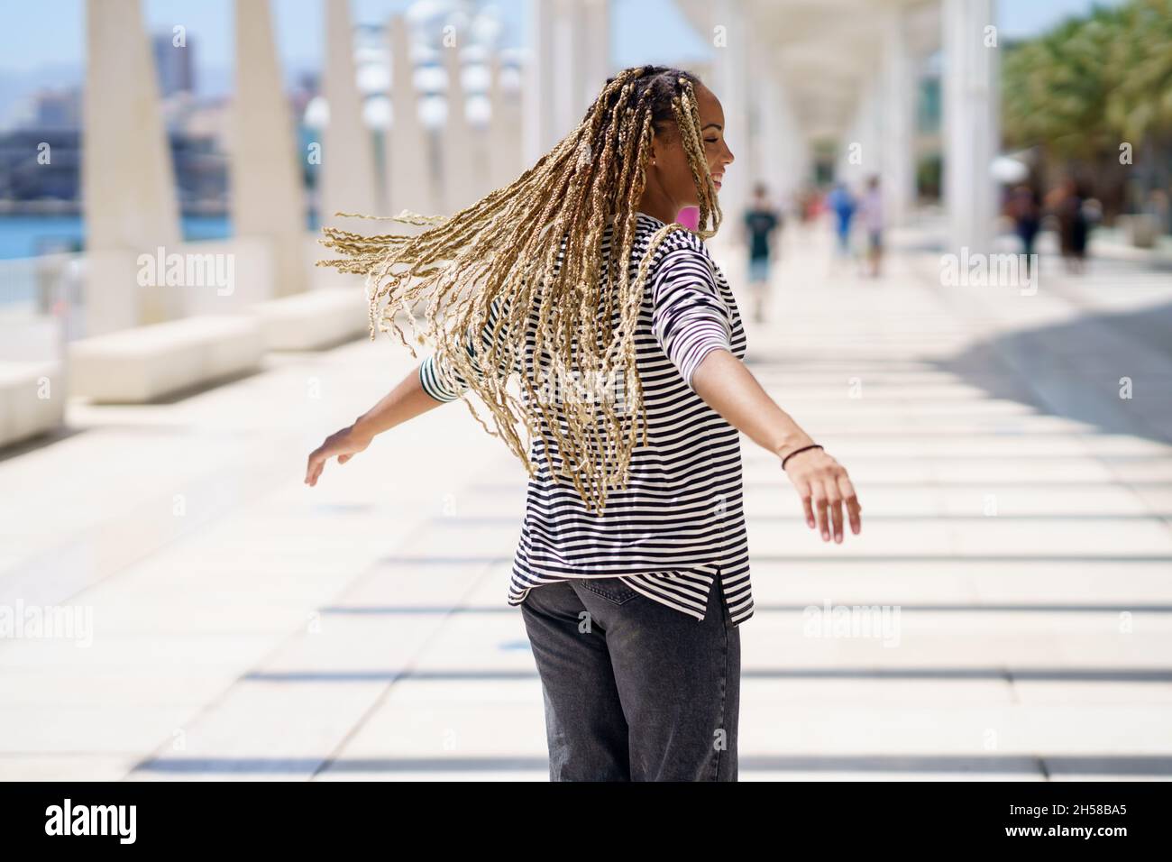 Young black female moving her coloured braids in the wind. Typical ...