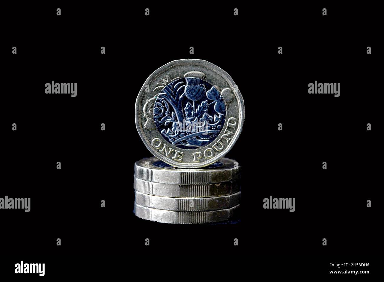 One pound coin balancing on its side on top of a column of pound coins ...