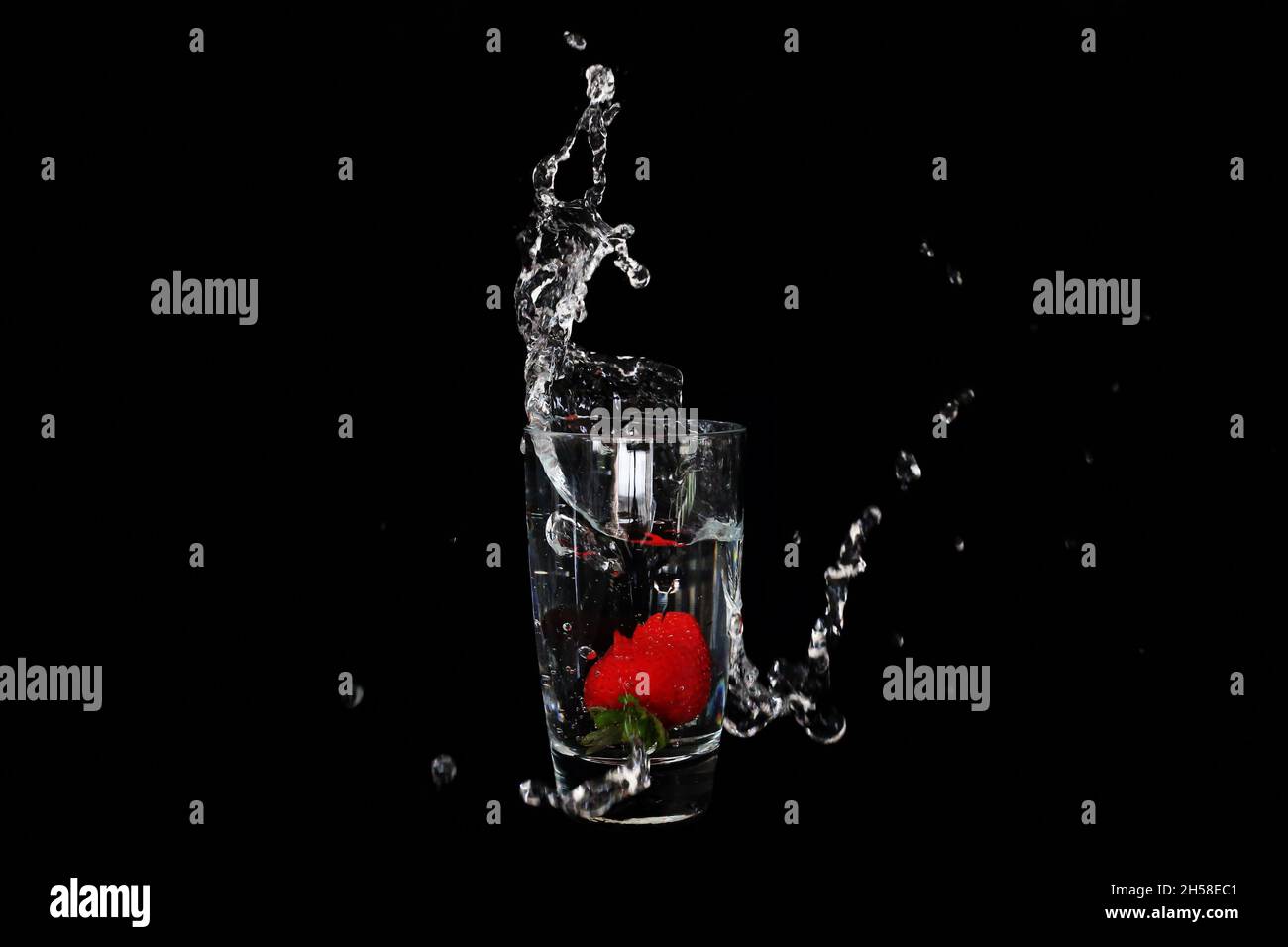 strawberry splash inside a glass of water - black background - high ...