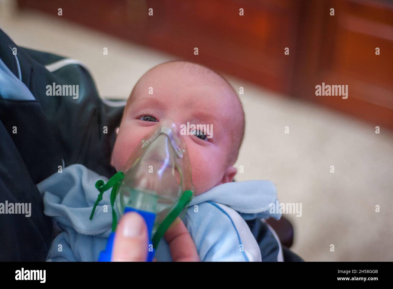 A closeup of a cute newborn its mother's arms, breathing with the help ...