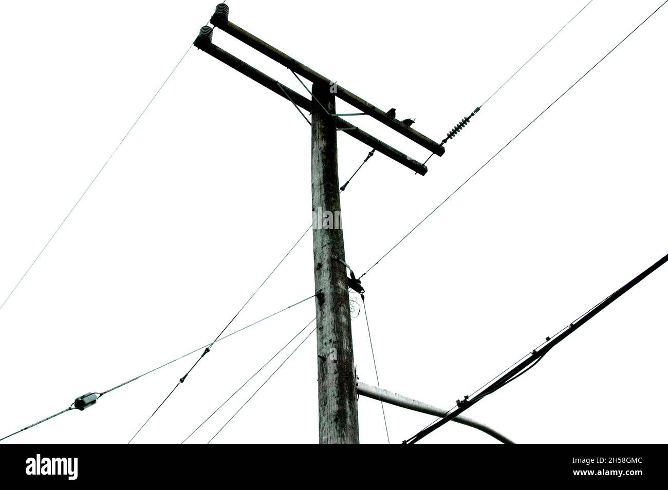 A low angle shot of transmission cables and an old metal pole under a ...