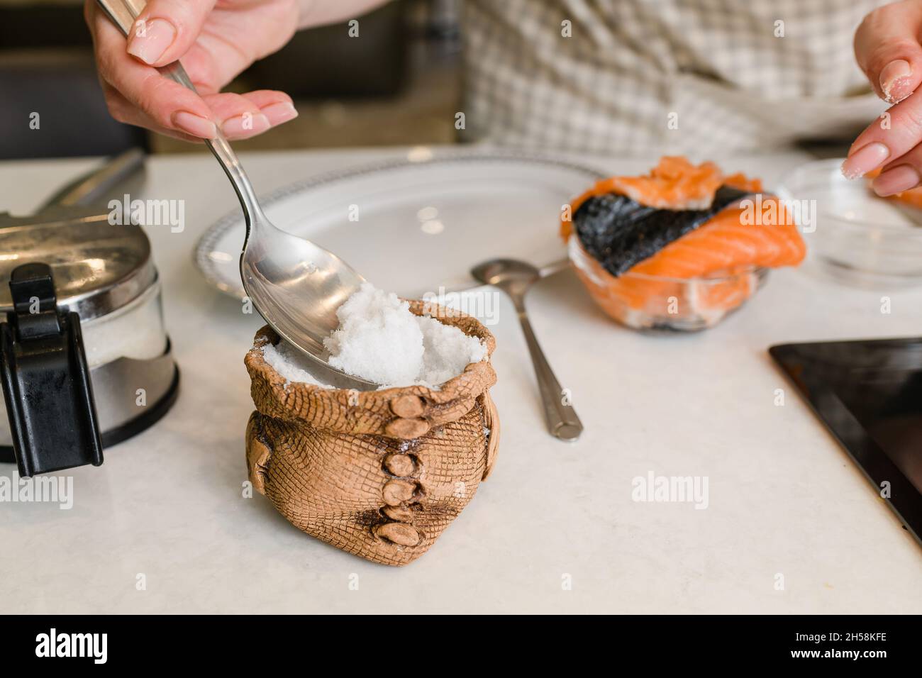 Female hand picks up a spoonful of salt. Woman cooking fish Stock Photo ...