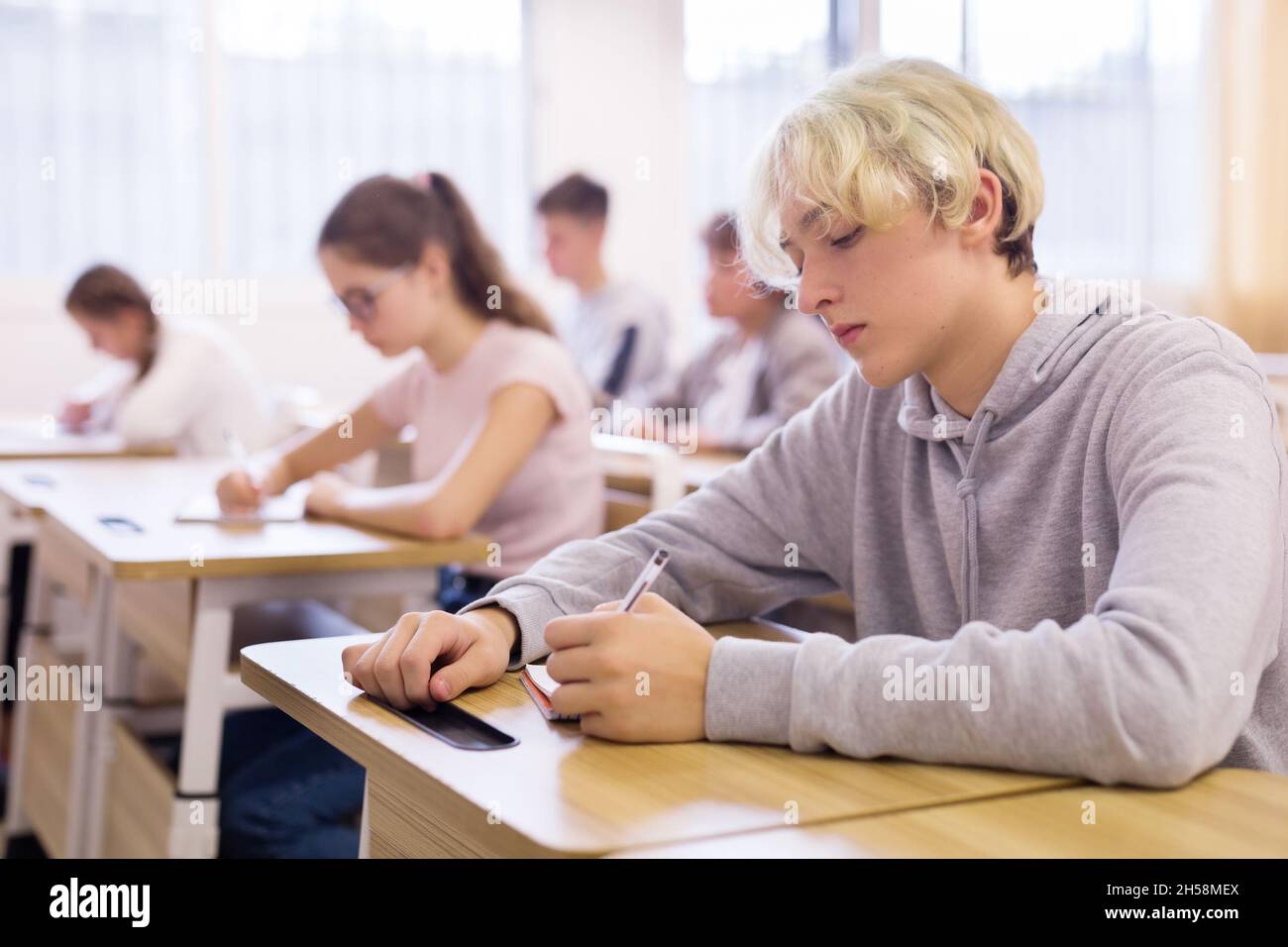 Teen boy sitting at desk in classroom Stock Photo - Alamy