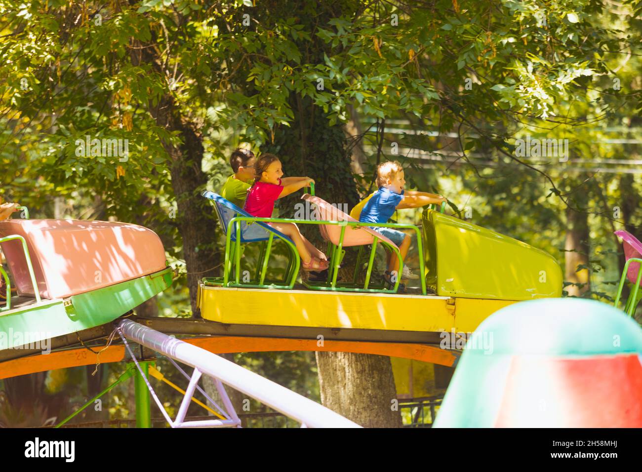 The happy kids on a roller coaster in the amusement park Stock Photo ...