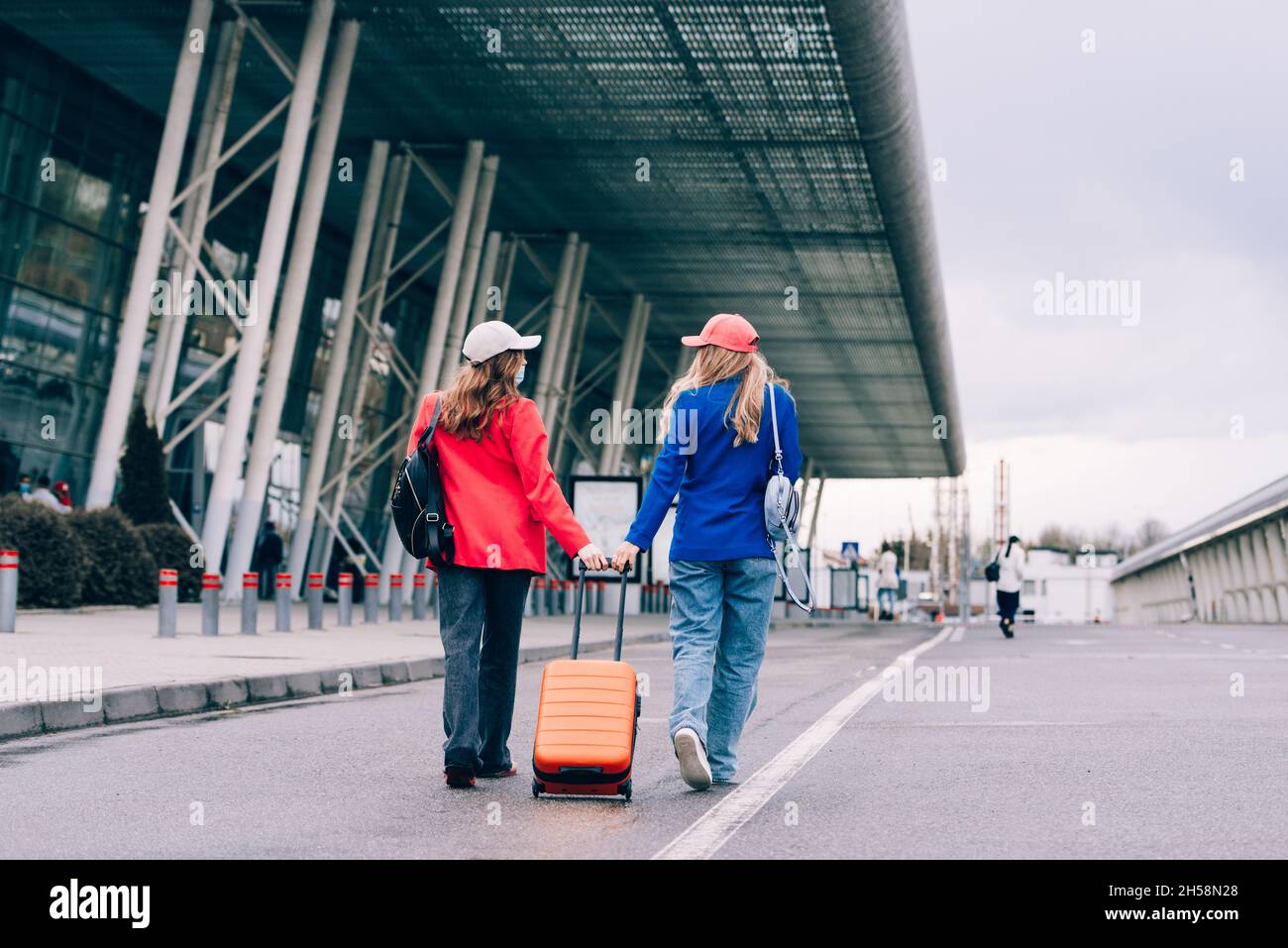 Two happy girls walking near airport, with luggage. Air travel, summer ...