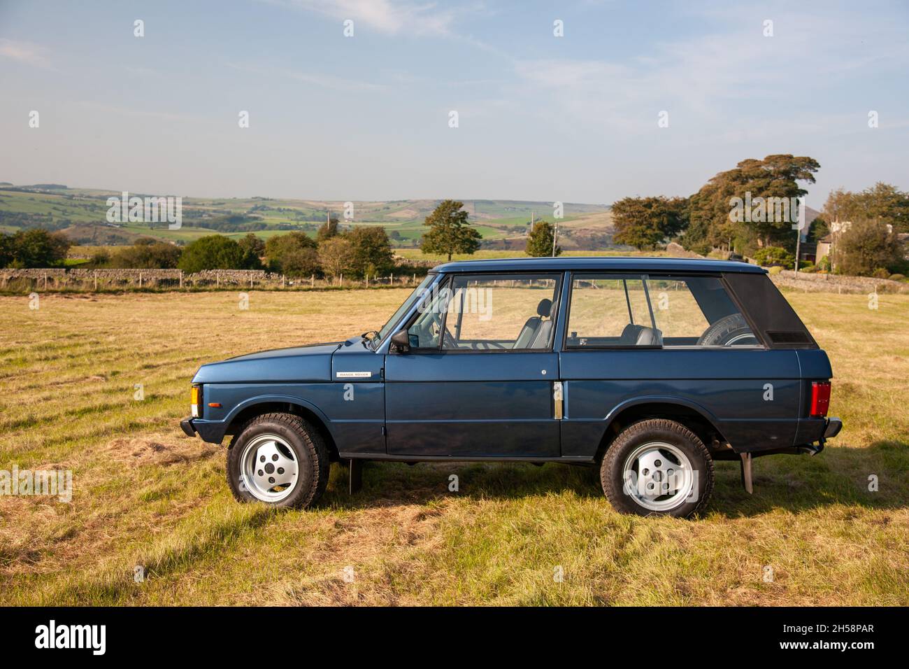 Early model two-door Range Rover parked on a farm field on a Summer ...