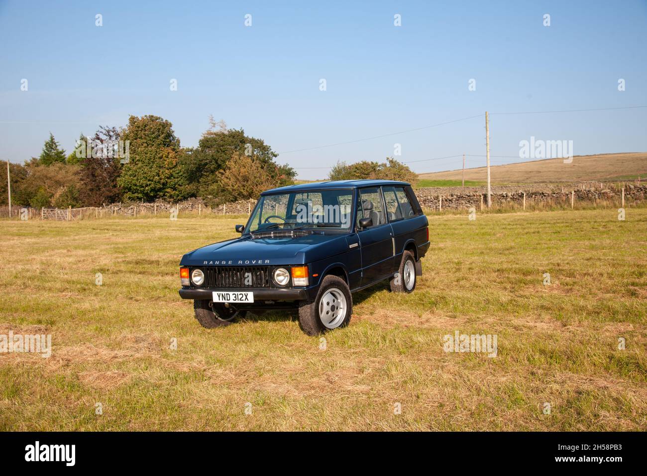 Early model two-door Range Rover parked on a farm field on a Summer ...