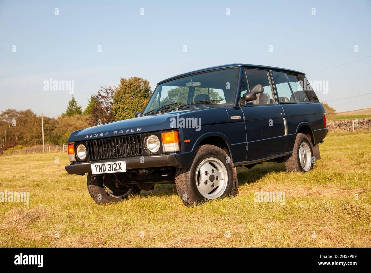 Early model two-door Range Rover parked on a farm field on a Summer ...
