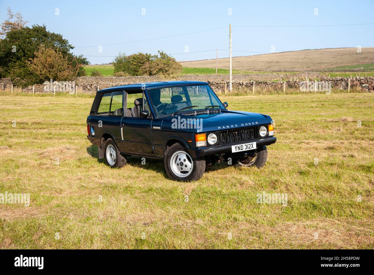 Early model two-door Range Rover parked on a farm field on a Summer ...