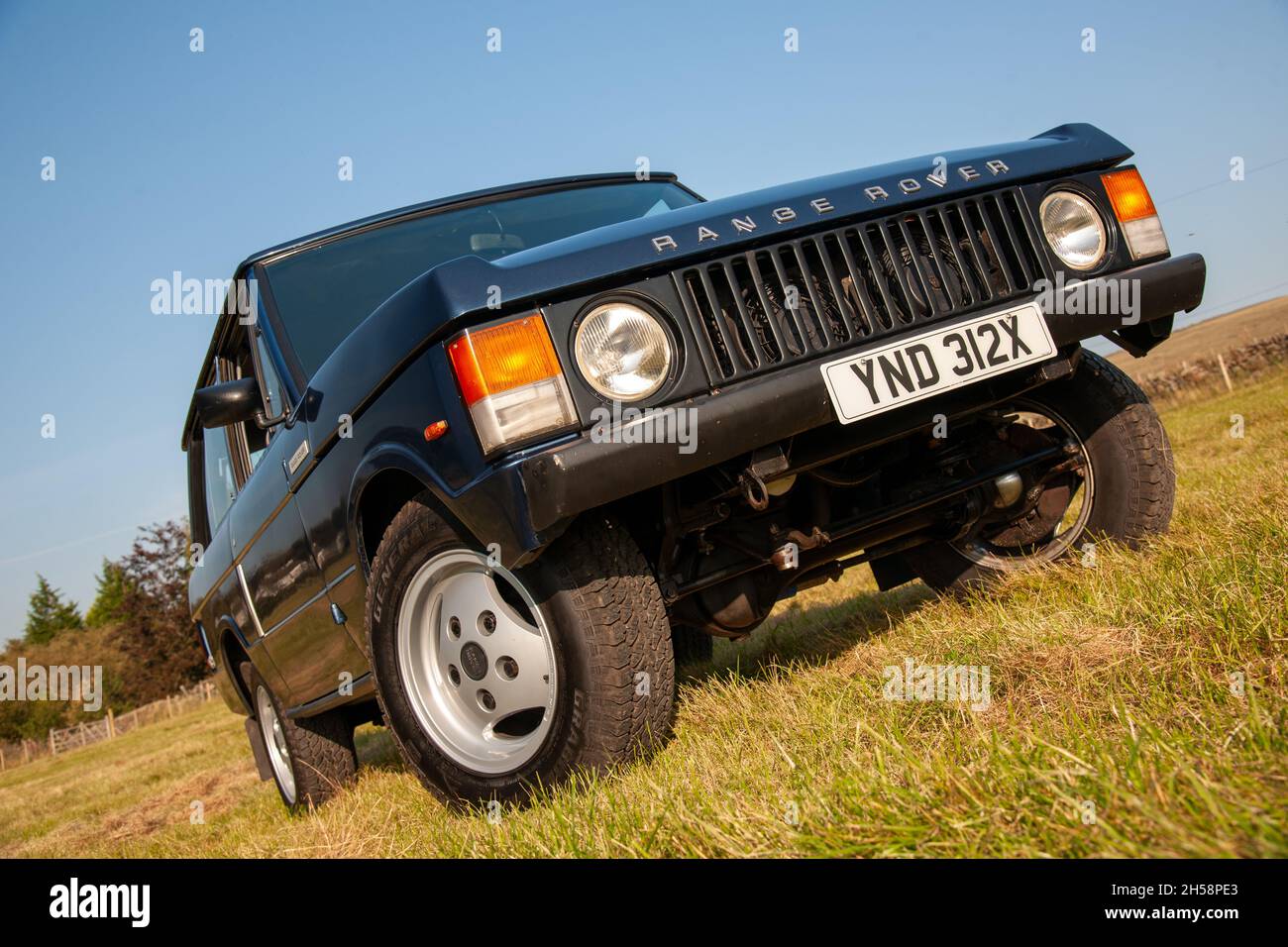 Early model two-door Range Rover parked on a farm field on a Summer ...