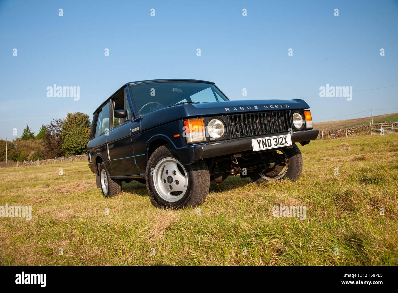 Early model two-door Range Rover parked on a farm field on a Summer ...