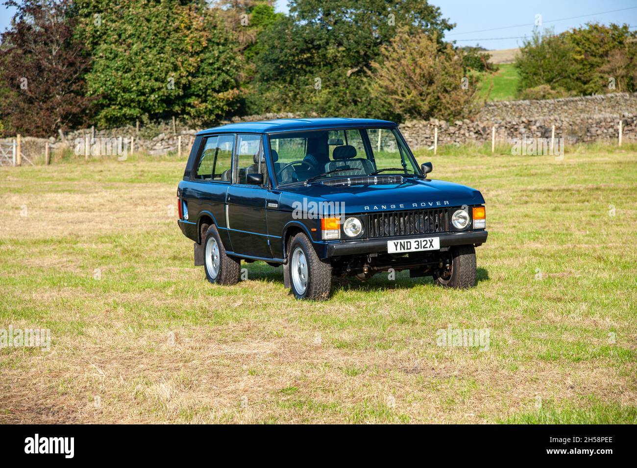 Early model two-door Range Rover parked on a farm field on a Summer ...