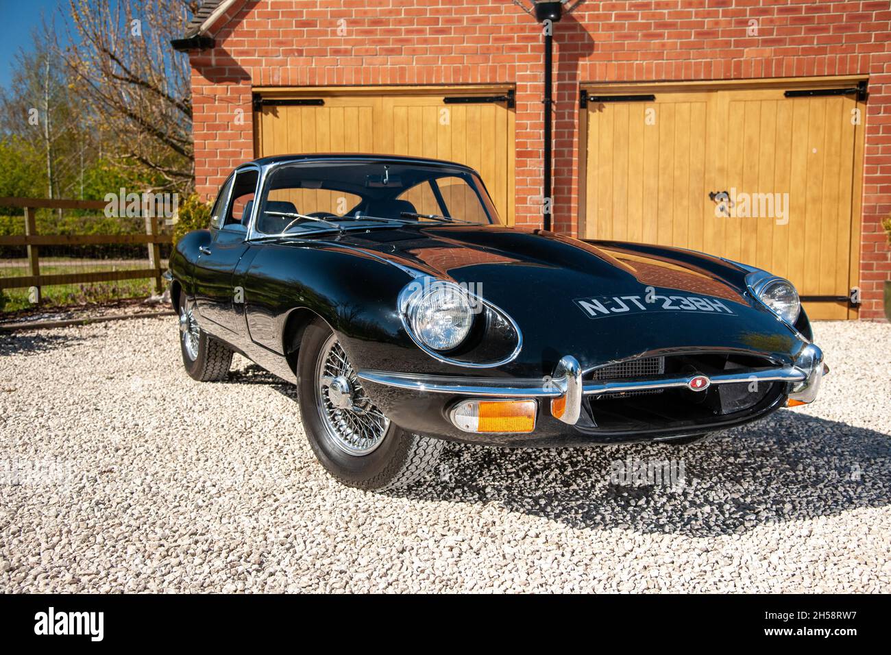 Black Jaguar E Type coupe with wire wheels parked in front of double ...
