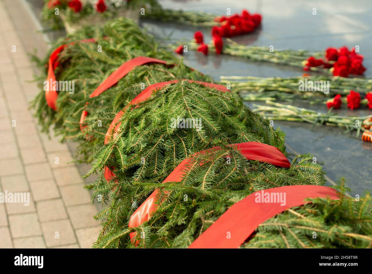 Spruce wreaths on the monument. Commemorative red ribbons on the grave ...