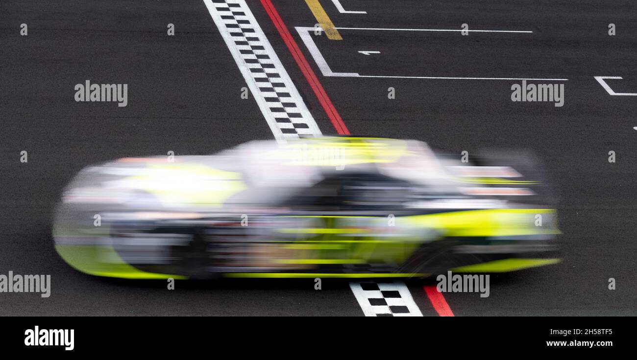 Blurred motion racing car crossing finish checkered line on asphalt ...