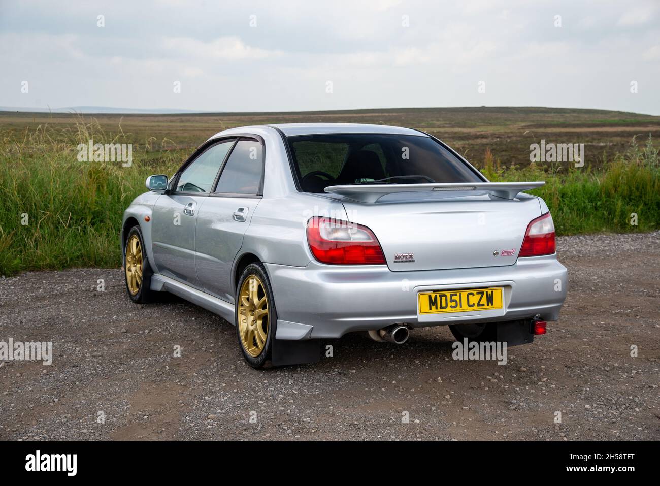Silver 2001 Subaru WRX XTI with gold wheels parked on gravel beside ...