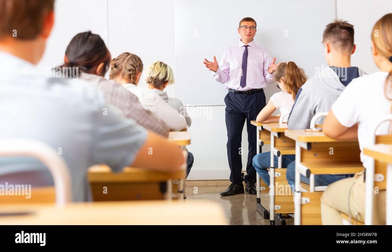 Adult teacher is giving lecture for students in class Stock Photo - Alamy
