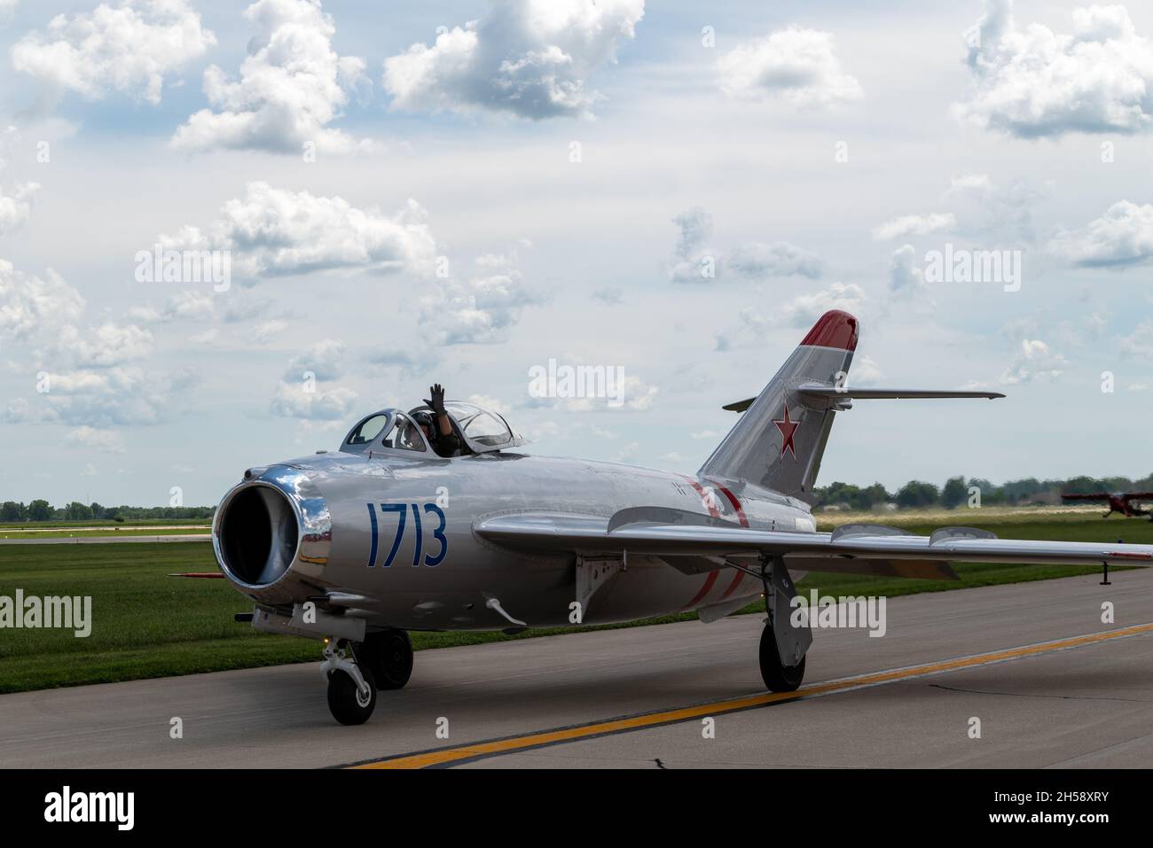 A vintage military aircraft taking off in an airbase under a cloudy sky ...