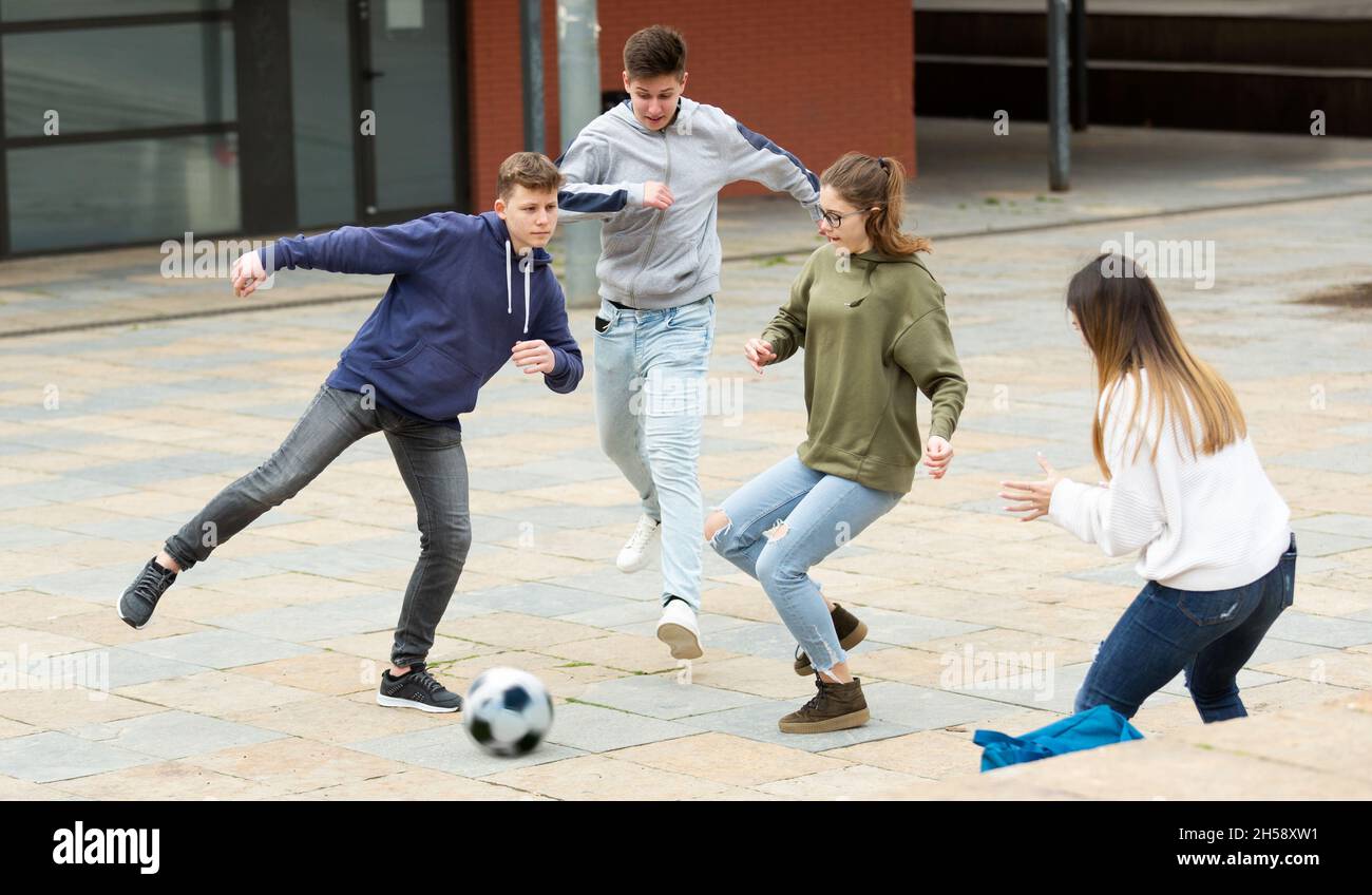 Company of glad teenagers playing football on street Stock Photo - Alamy
