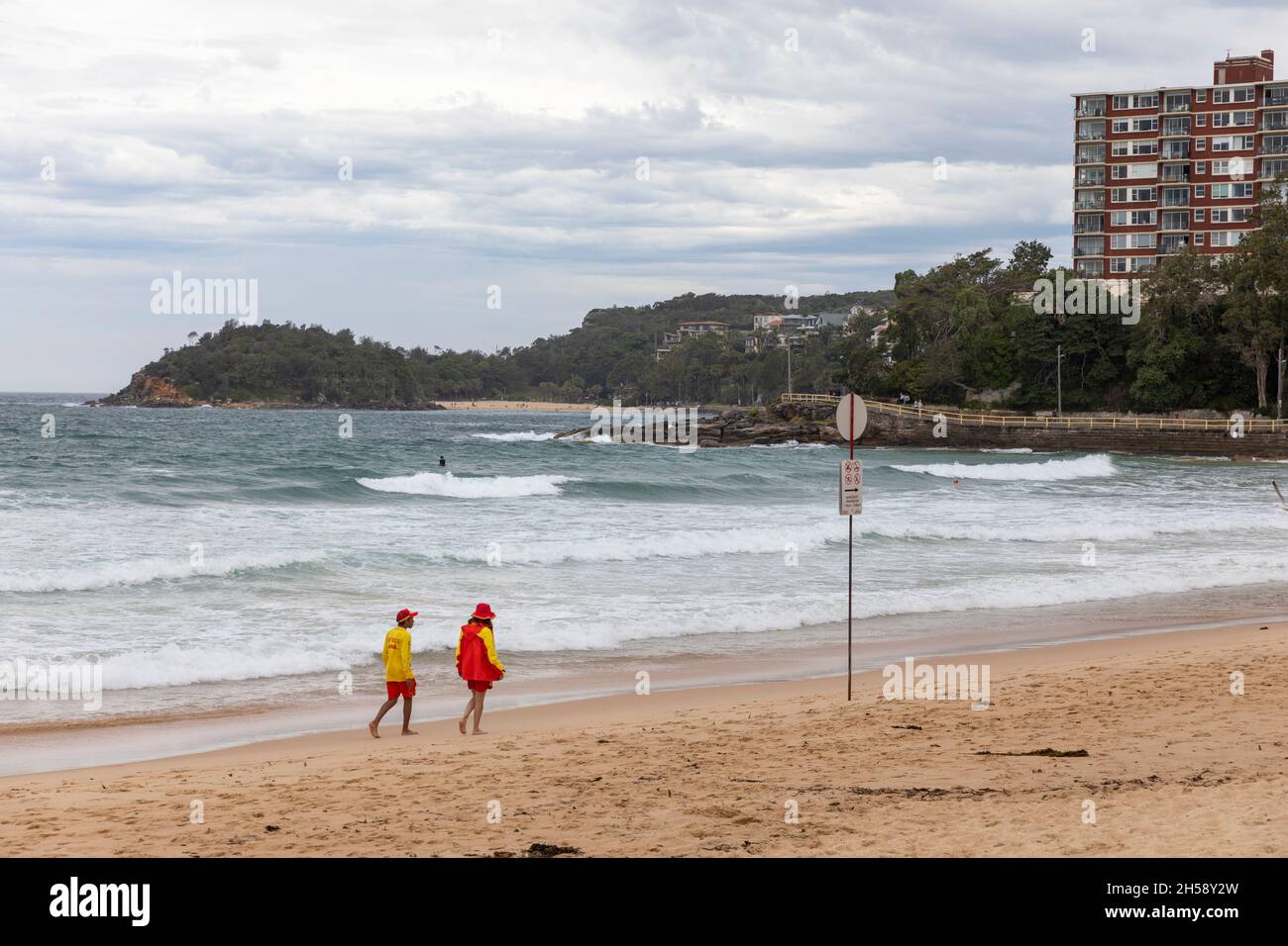 Surf rescue volunteer lifesavers walking along the shore of Manly Beach ...