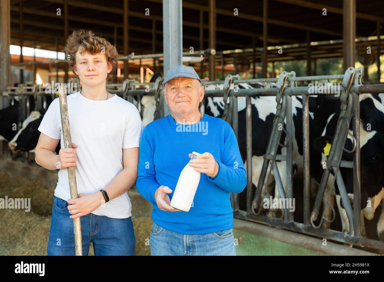Portrait of an elderly farmer and his young assistant with bottle of ...