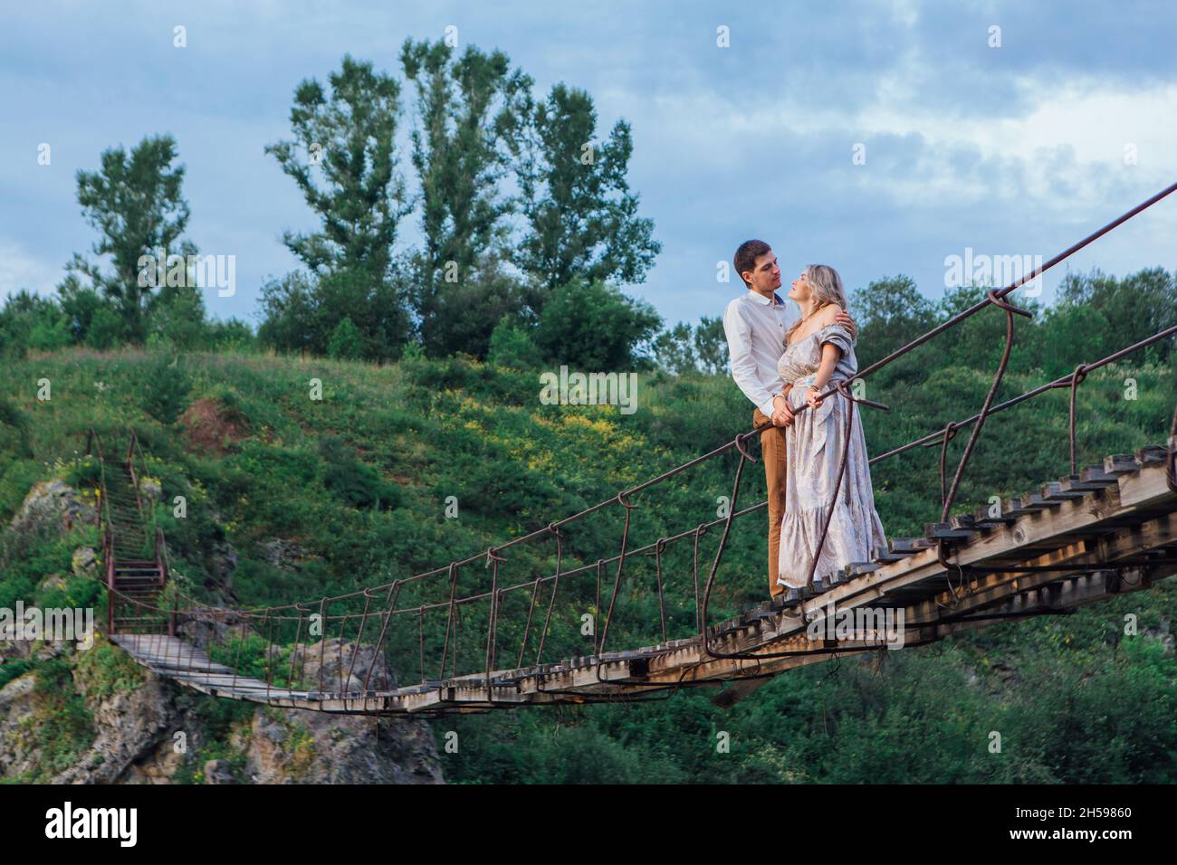 Beautiful young romantic couple standing and hugging on the suspension ...