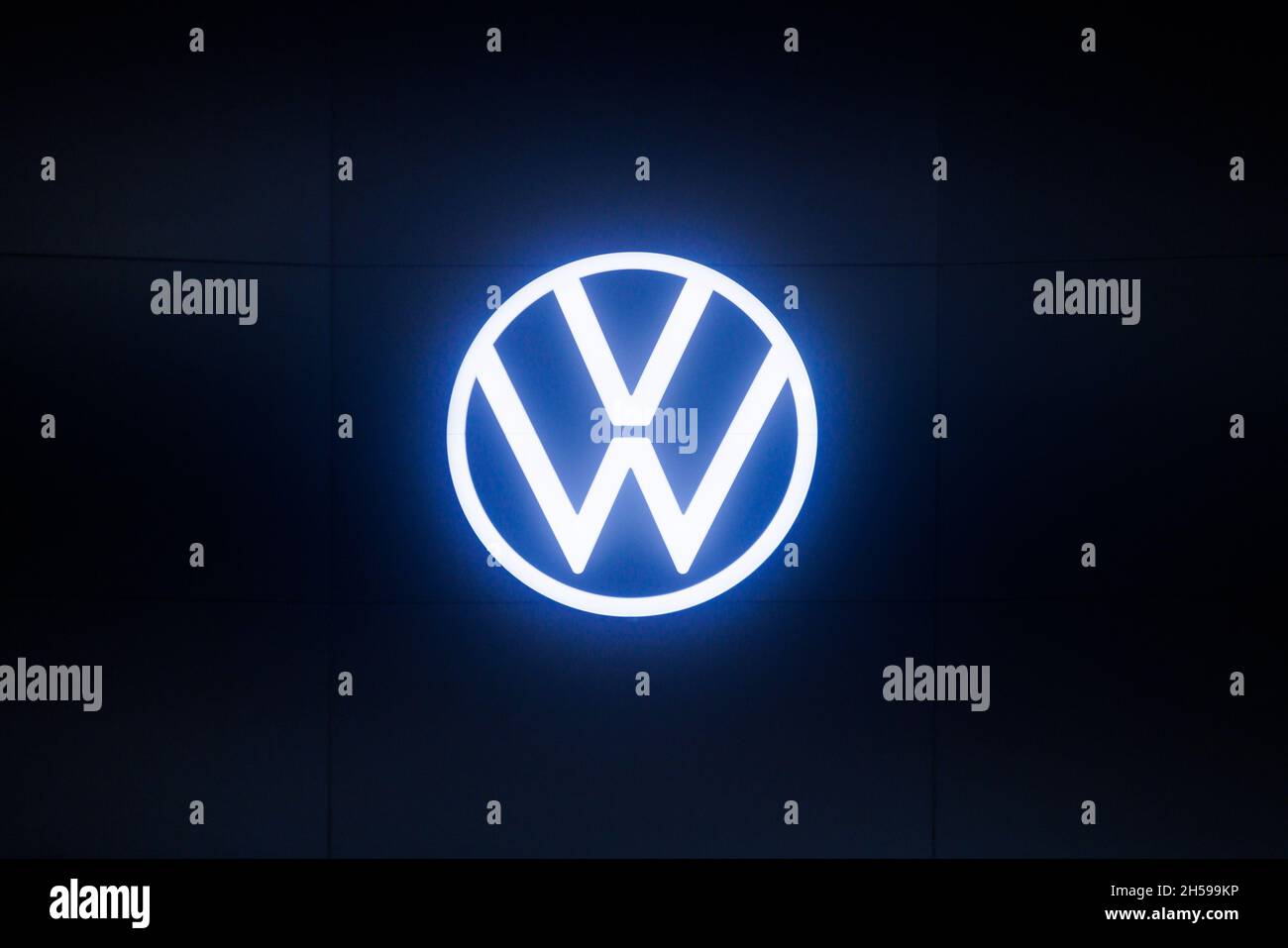 glowing round volkswagen logo on outside white building wall at foggy ...