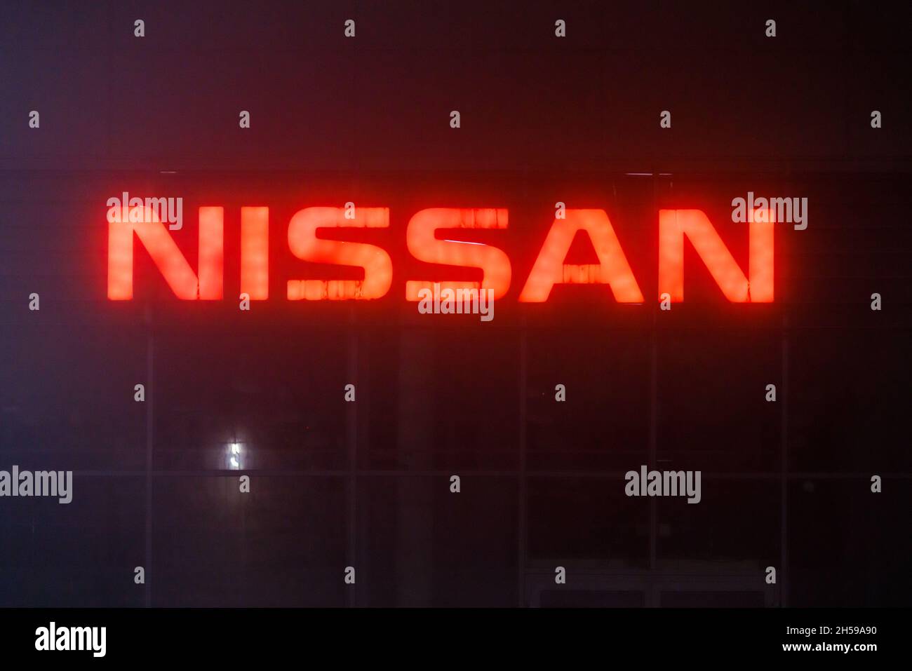 neon red sign Nissan on car dealership center at foggy night Stock ...
