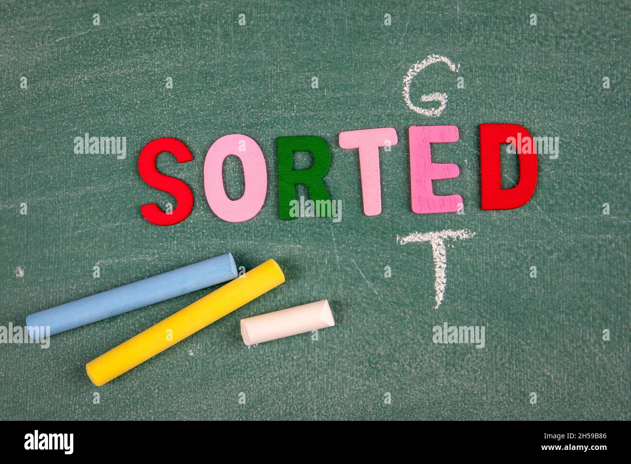 Get Sorted concept. Words and colored pieces of chalk on a green chalk ...