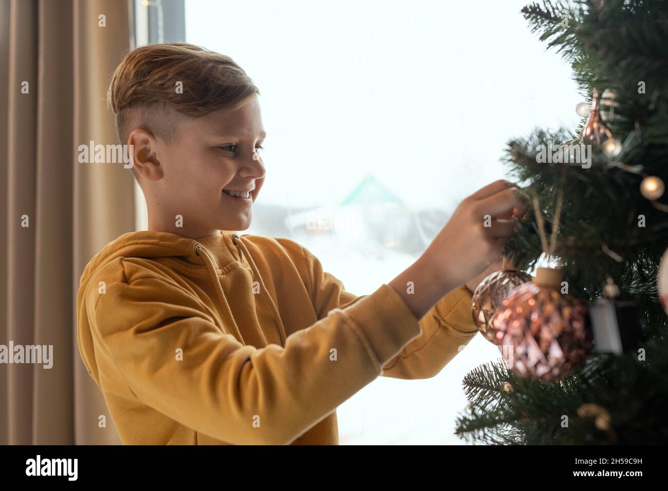Happy boy in anticipation of New Year standing at Christmas tree and ...