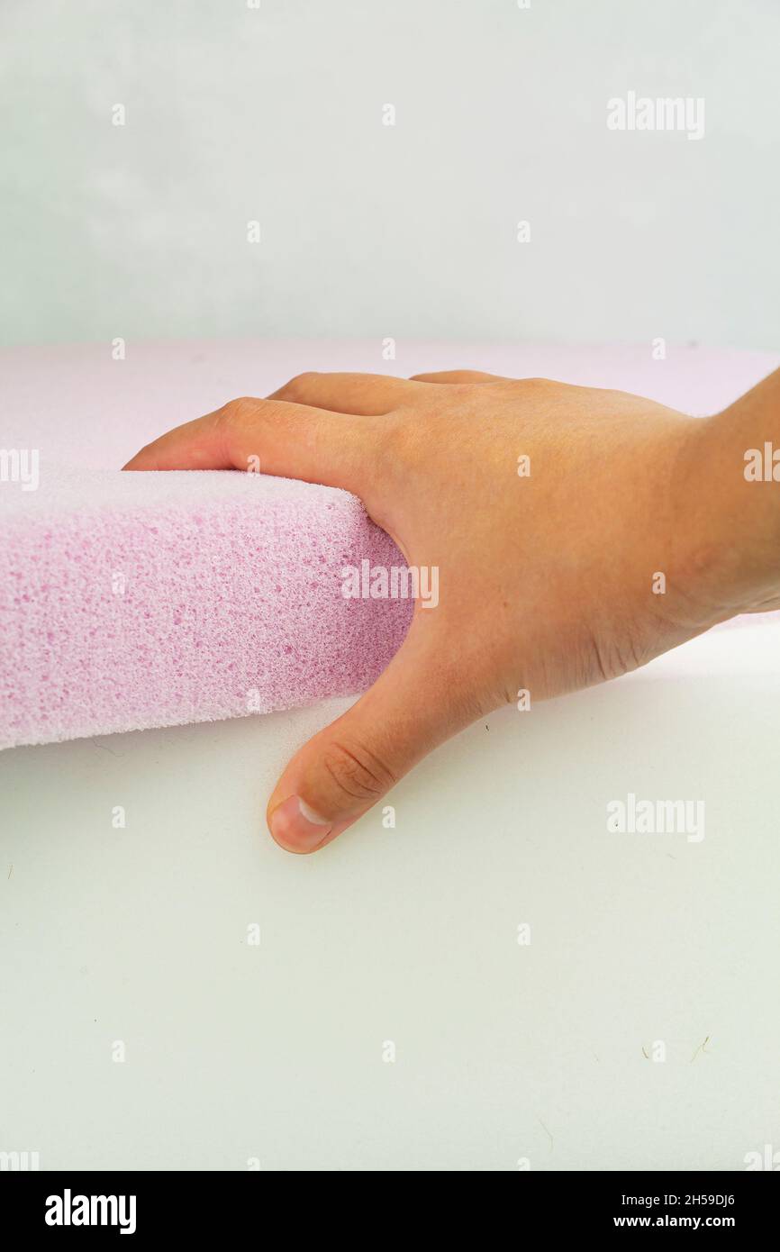 the hand presses on the surface of the rubber foam. Checking hardness ...