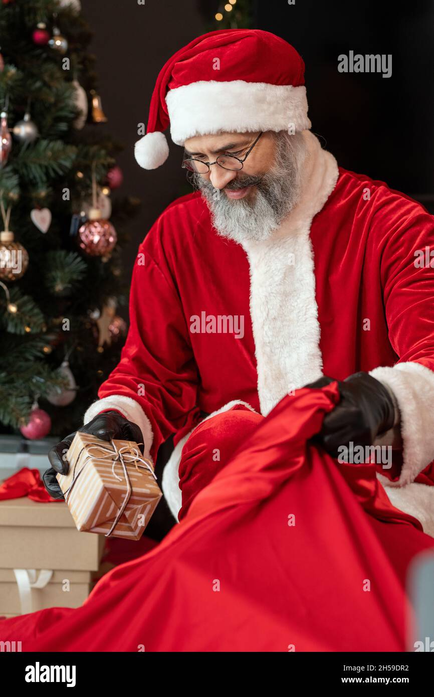 Smiling Santa Claus in leather gloves and red costume stealing presents ...
